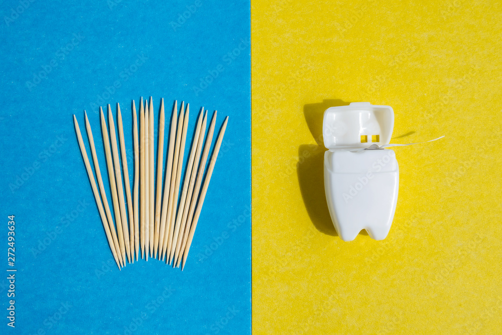 toothpicks on blue background and dental floss in white container on ...