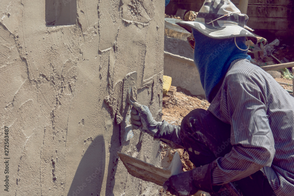 Construction workers plastering building wall using cement plaster ...