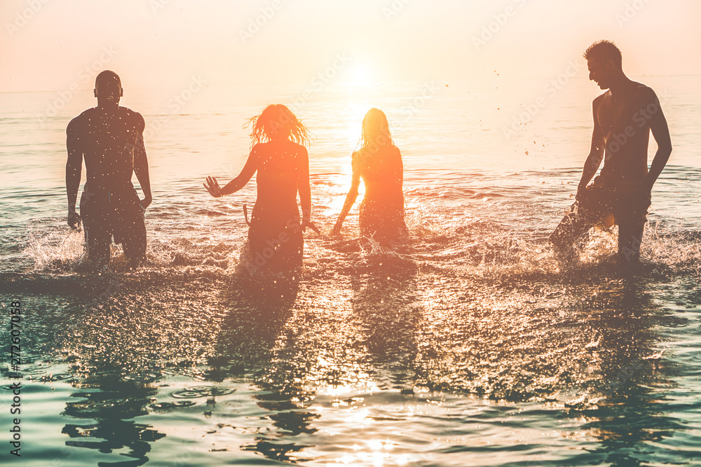 Happy friends swimming on tropical beach at sunset - Group of young ...