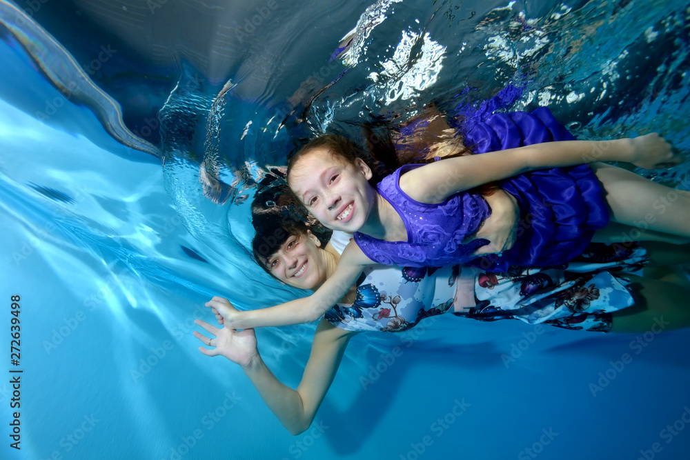 Happy mom and little daughter hugging, floating underwater, holding ...