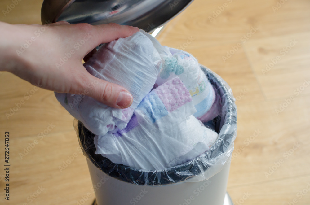 Woman hand put used diaper to the Trash bin full of used diapers. Close ...