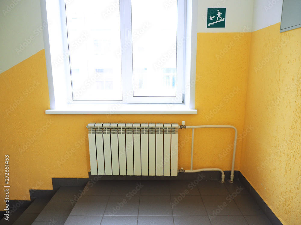 Corridor, window with radiator, yellow painted wall and a sign warning ...