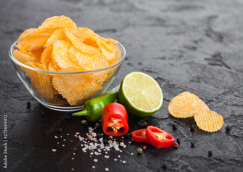 Glass bowl plate with potato crisps chips with paprika flavour on black ...
