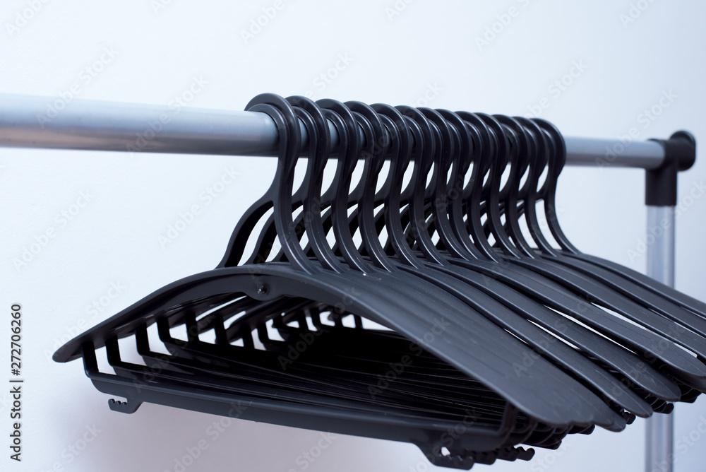 black plastic hangers hang on a light background. many different ...