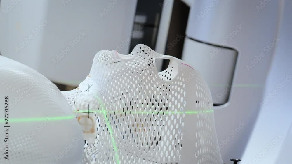 Radiation therapy machine rotates around a plastic mask of a patients ...