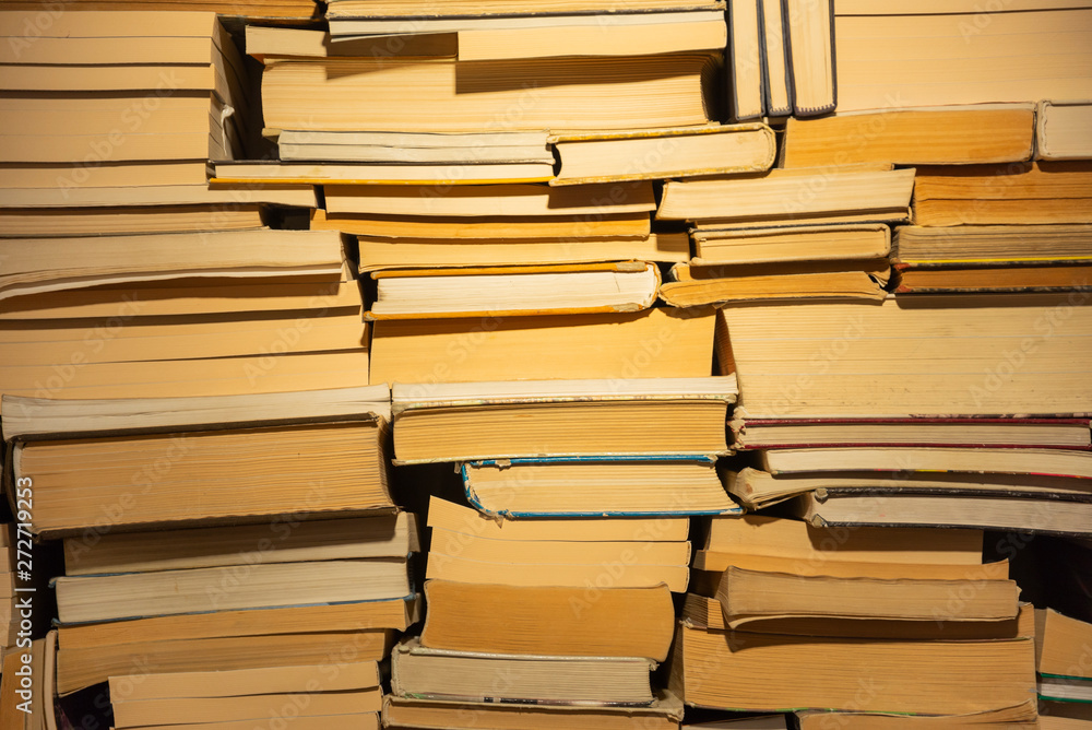 Stack of books of different size on the shelf. View from the butt on ...