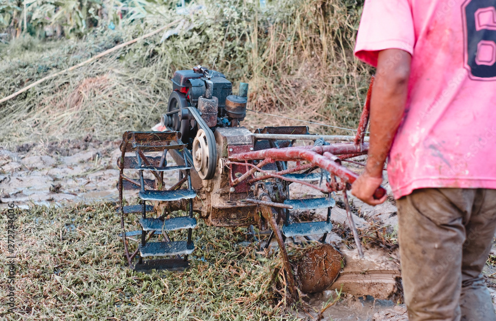 Farmer using tiller two wheel tractor for preparing soil on the field ...