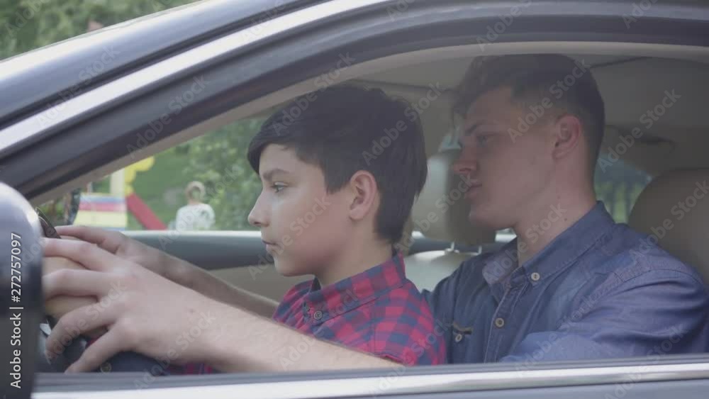 Young father teaching his son to drive the car close up. The boy ...