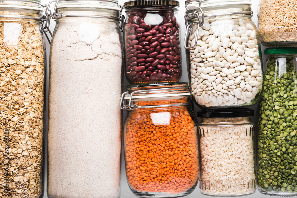 Variety of grains and legumes in glass jars, top view. Zero waste ...
