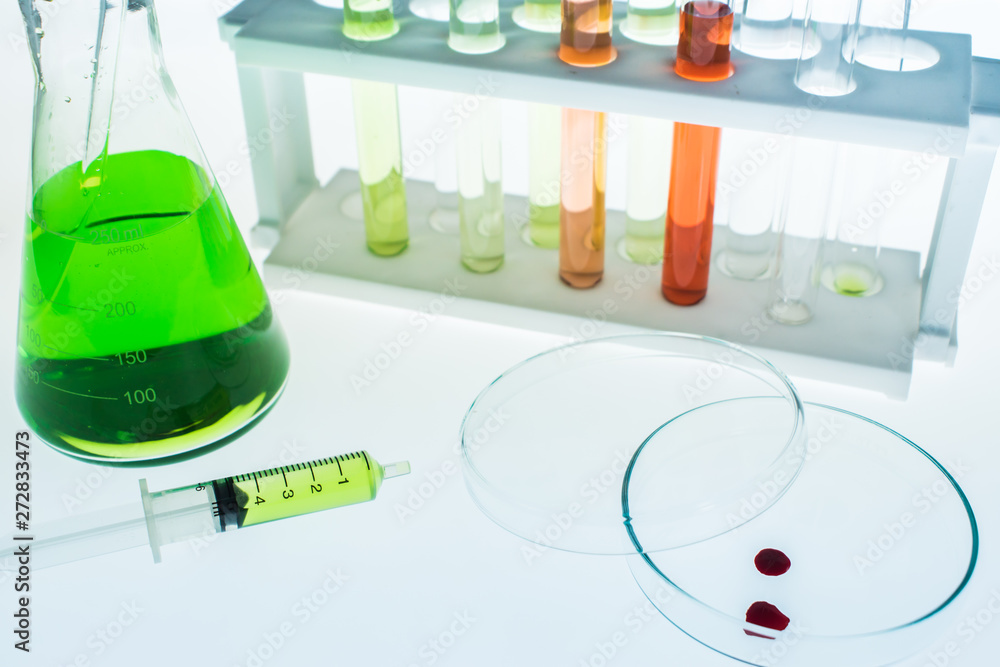 Erlenmeyer flask, Petri dish, Test tubes and a syringe with drops of ...