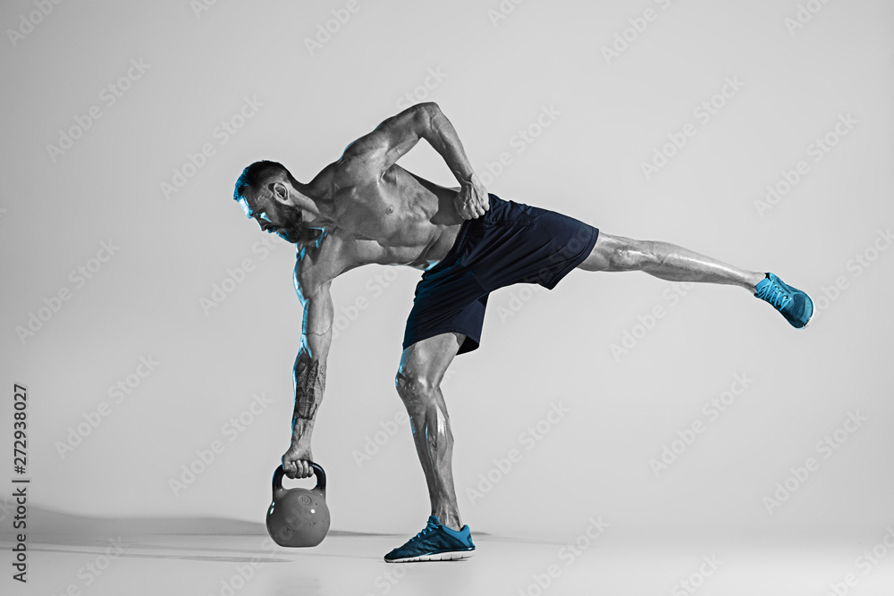 Ready and hardy. Young caucasian bodybuilder training over studio ...