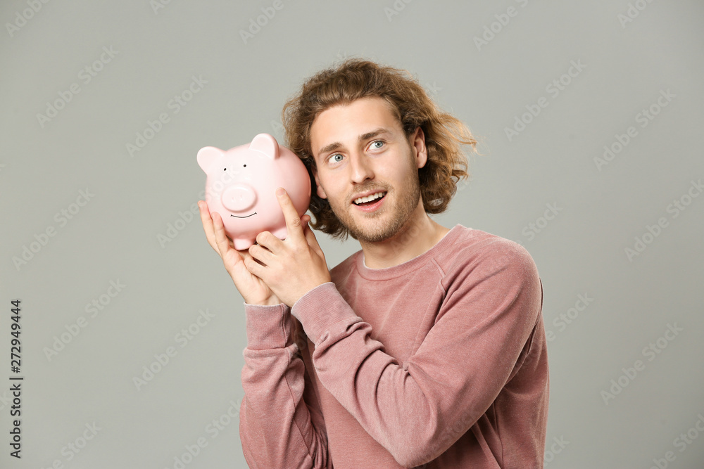 Handsome man with piggy bank on grey background Stock Photo | Adobe Stock