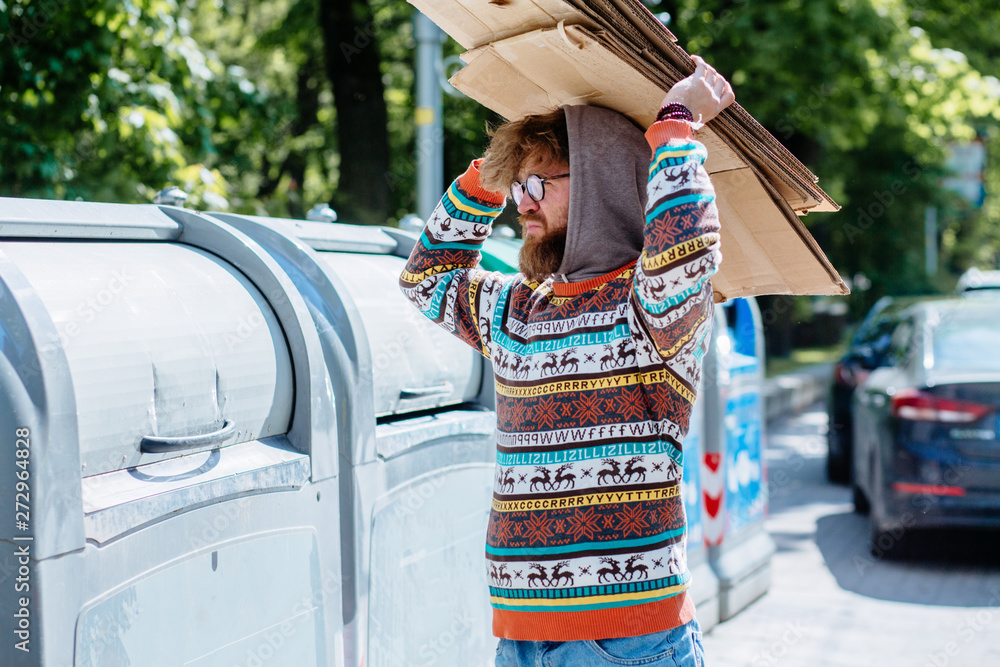 Homeless beard man collecting waste paper. Stylish beggar taking carton ...