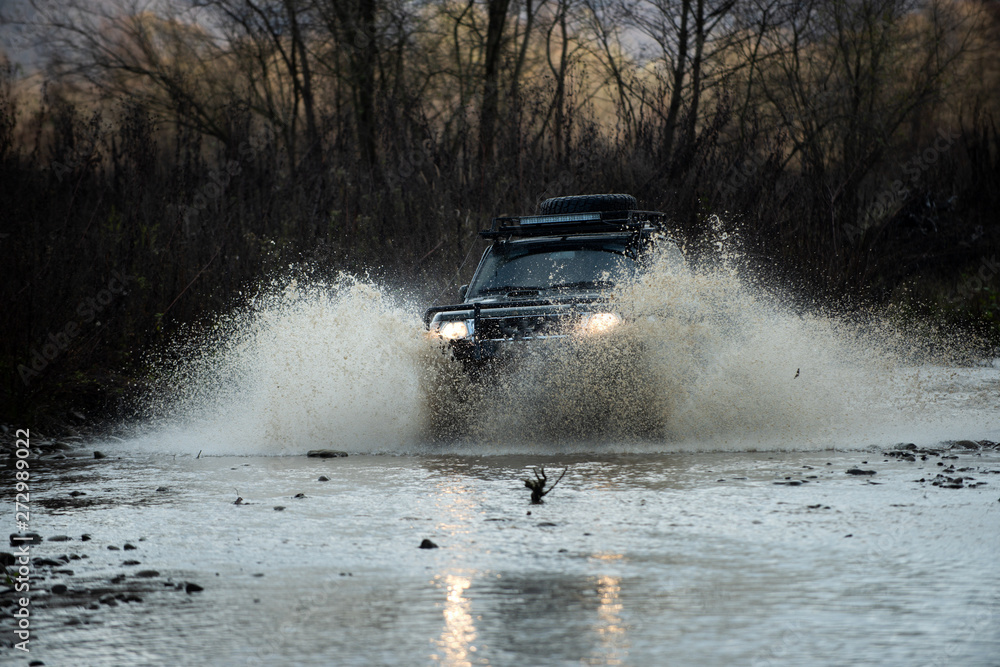 Off road vehicle coming out of a mud hole hazard, mud and water splash ...