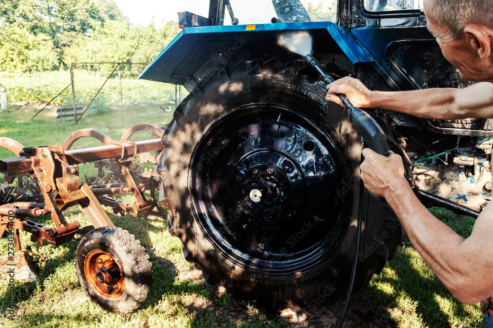 Man washes tractor wheels spraying pressure washer for tractor wash ...