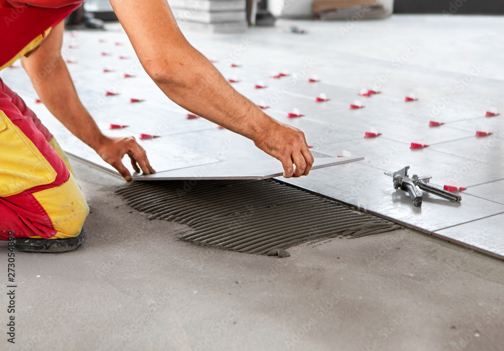 Ceramic Tiles. Tiler placing ceramic wall tile in position over ...