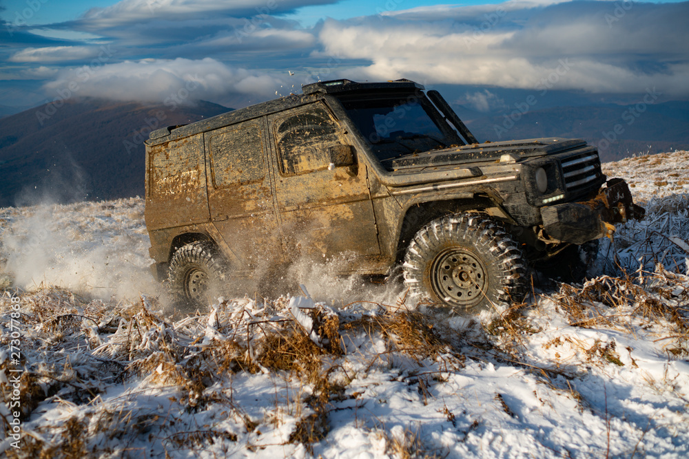 Front view of massive 4x4 off-road car on the dirty snowed ground ...