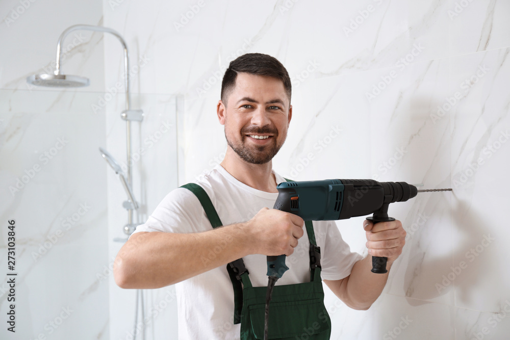 Handyman working with drill in bathroom. Professional construction ...