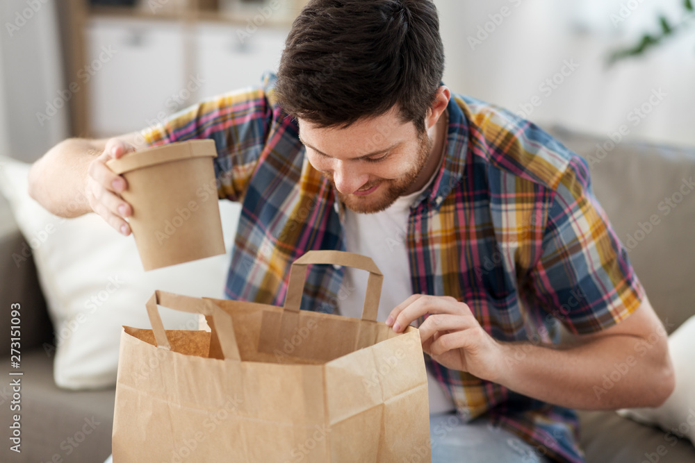 consumption, eating and people concept - smiling man unpacking takeaway ...