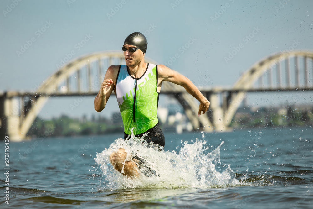 Professional triathlete swimming in river's open water. Man wearing ...