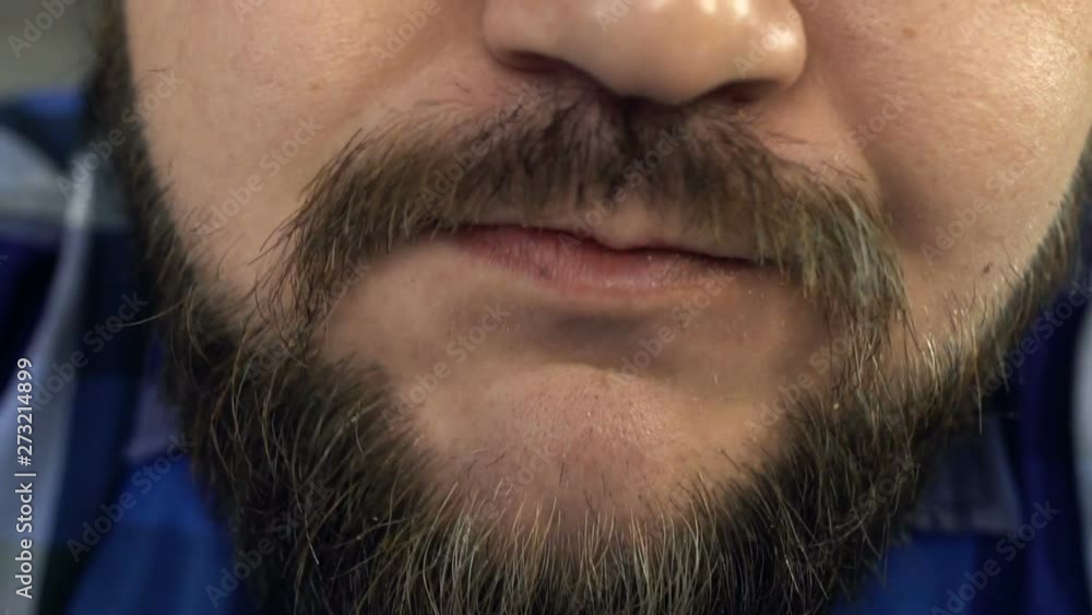 Closeup A fat man with a beard and a mustache shoves chips in his mouth ...