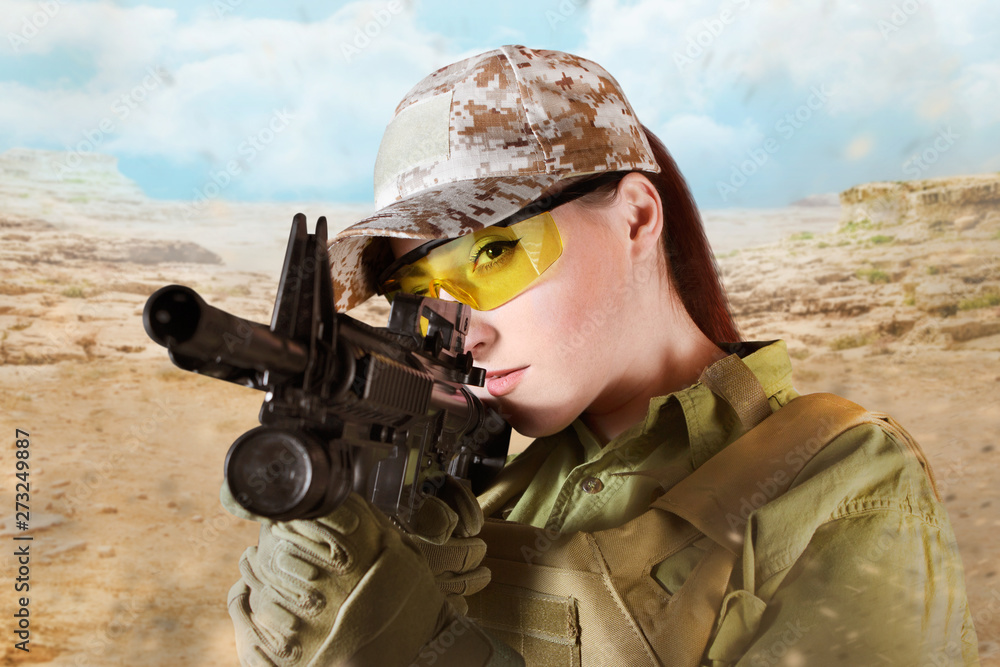 Beautiful young soldier woman in military uniform aiming at the enemy ...