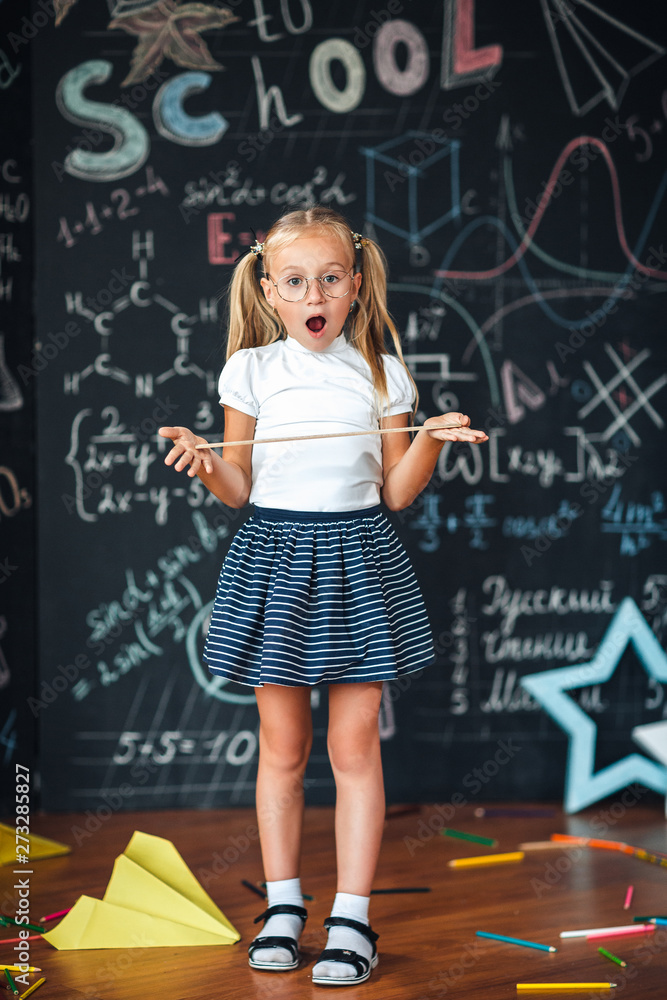 Little blonde girl with a surprised face with a ruler in her hands ...