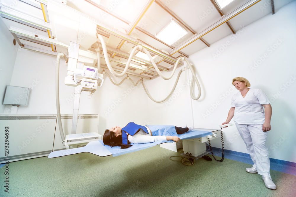 Radiologist and patient in a x-ray room. Classic ceiling-mounted x-ray ...