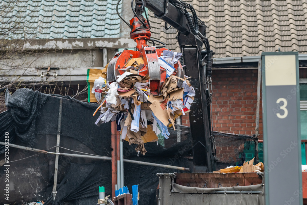 Grappling claw-machine collecting trash for recycling in front of an ...