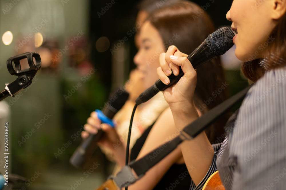 Selected focus microphone and unrecognizable female singer on stage ...