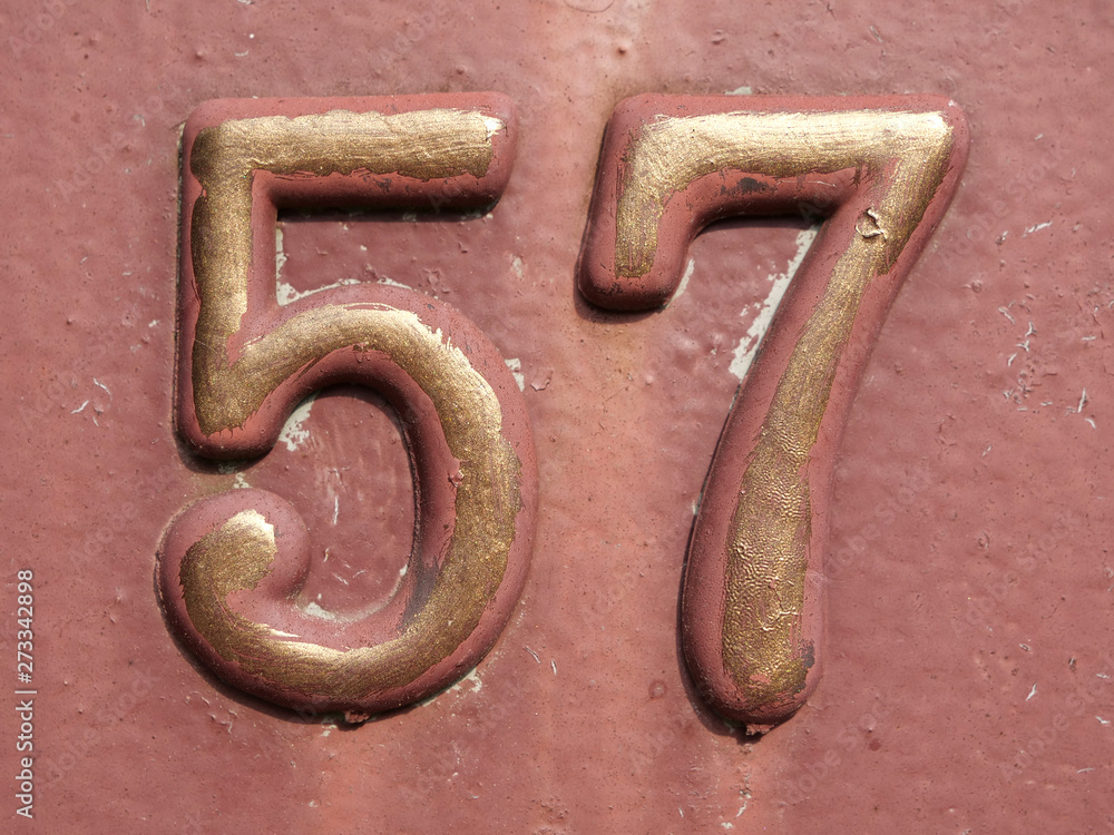 House number fifty seven. Number fifty seven door plate on red metal ...