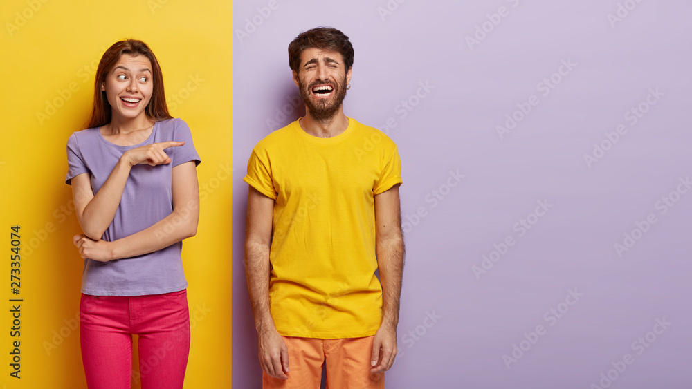 Funny smiling woman points at dejected guy with sorrowful expression ...