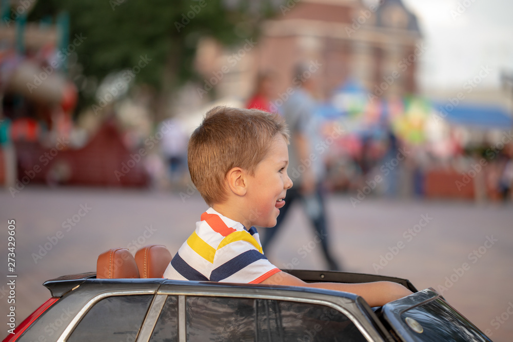 Cute boy in riding a black electric car in the park. Funny boy rides on ...