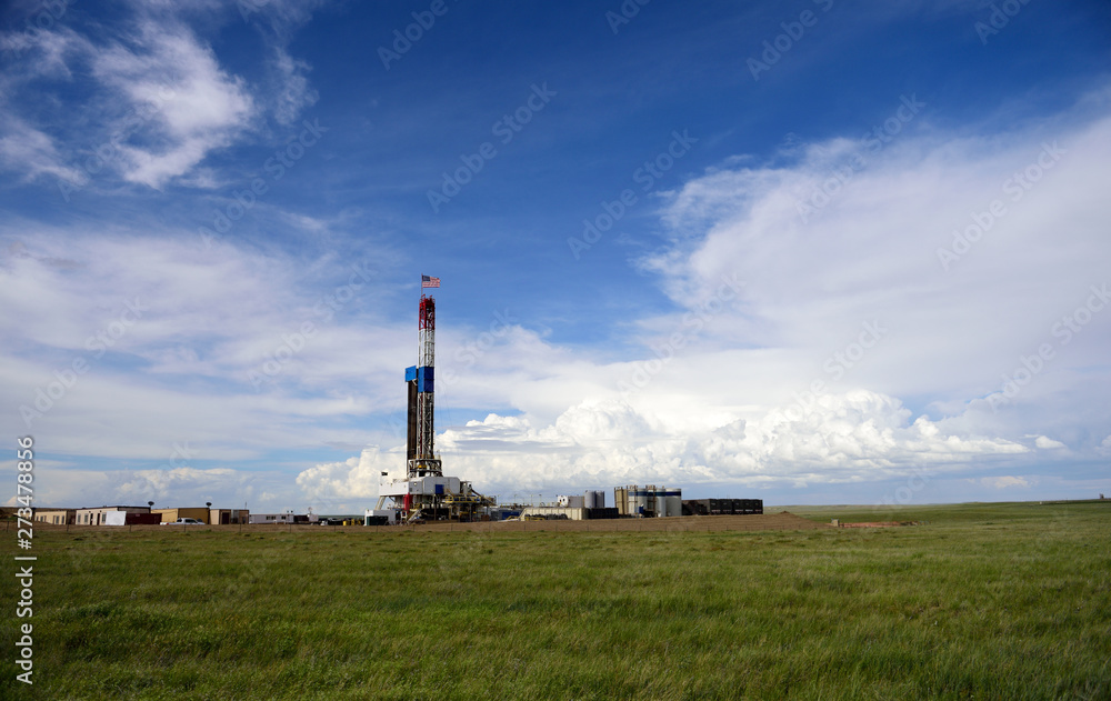 Crude oil exploration well site and drilling rig, blue sky and clouds ...