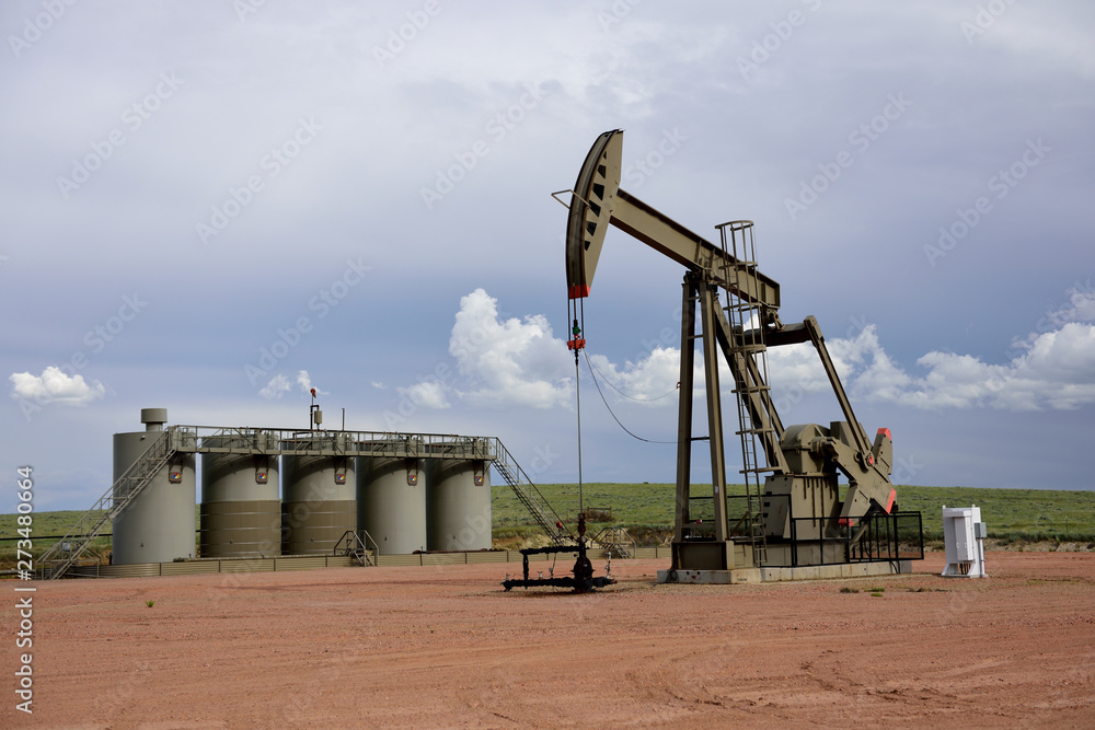 Crude oil well site pump jack and production storage tanks in the ...