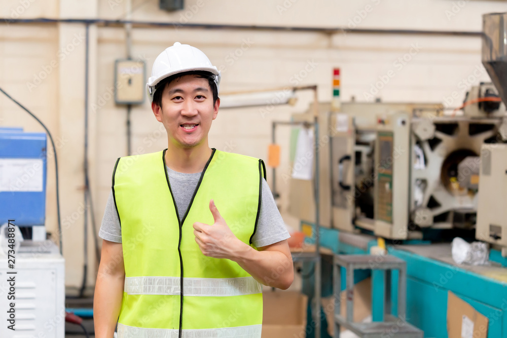 Front view of Asian factory worker with safety hard hat posed looking ...