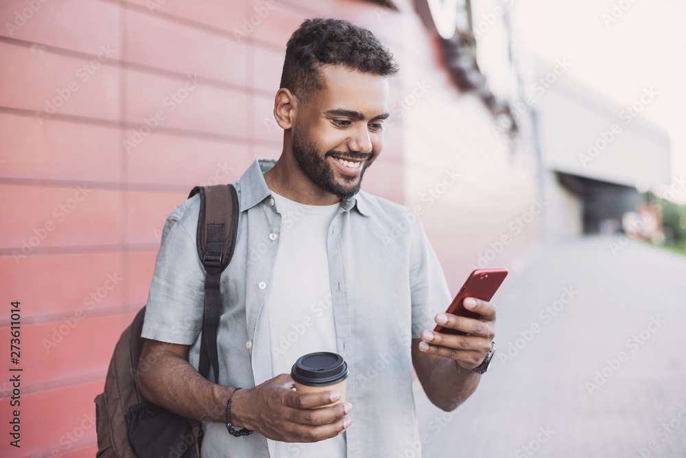 Young handsome man using smartphone in a city. Cheerful men holding ...