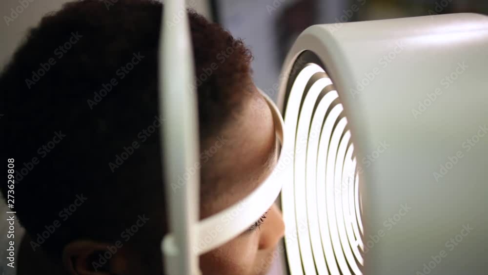 side view of an afro woman in an optometry cabinet correcting her ...