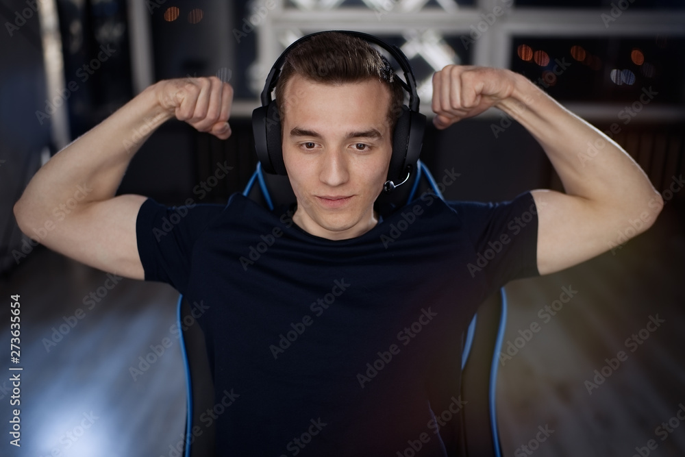 Back view of young gamer guy in headphones screaming and rejoicing ...