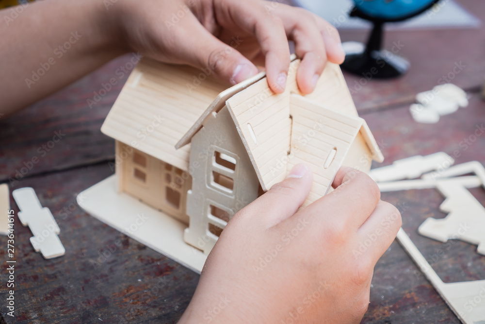 Asian boy building toy house or jigsaw home at outdoor near globe ...