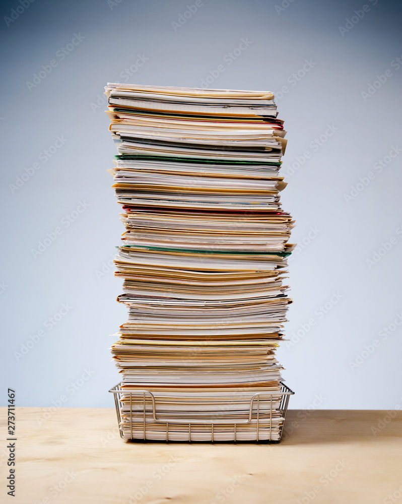 In, out tray on desk with tall stack of never ending office paperwork ...