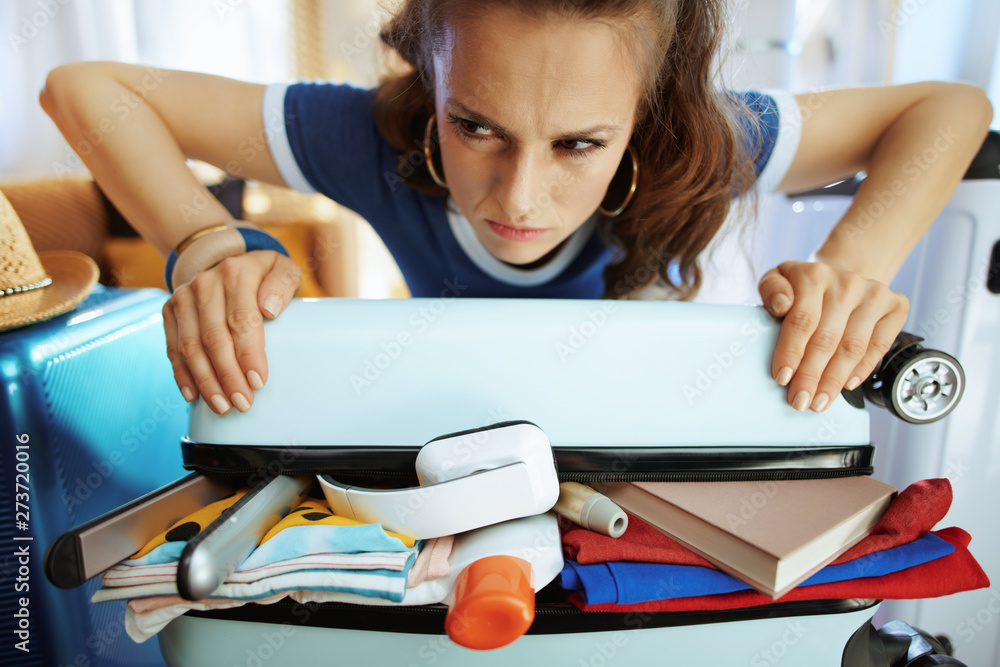 stylish tourist woman trying to close overload bag Stock Photo | Adobe ...