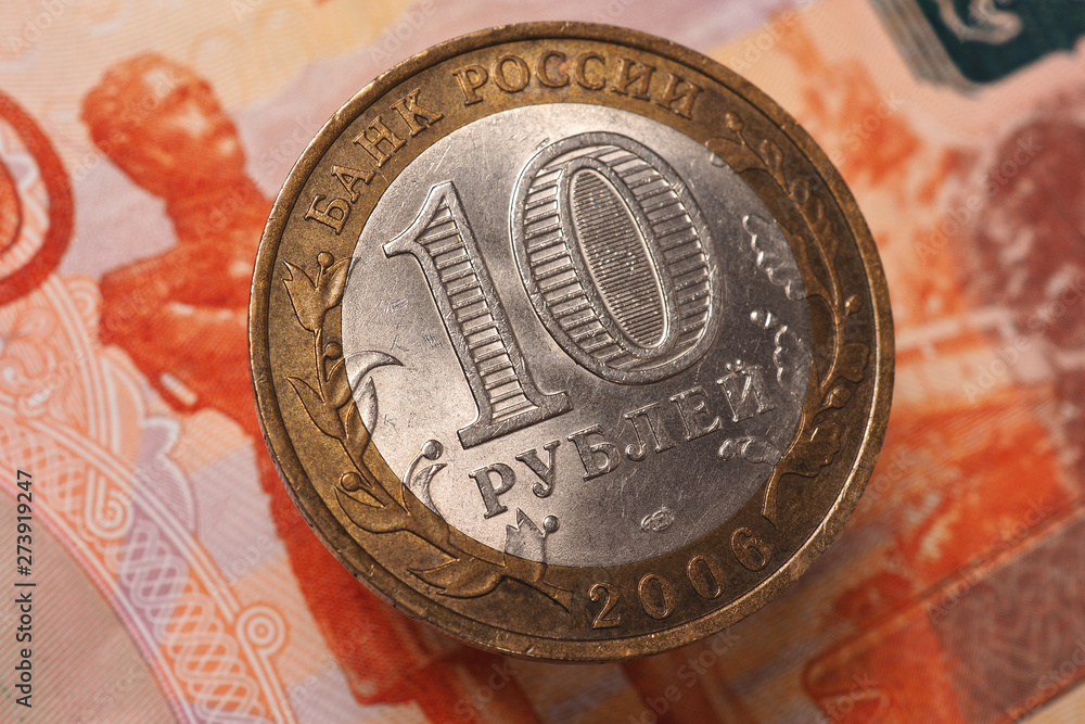 Russian bimetallic 10-ruble coin hangs in the air over a 5000 ruble ...