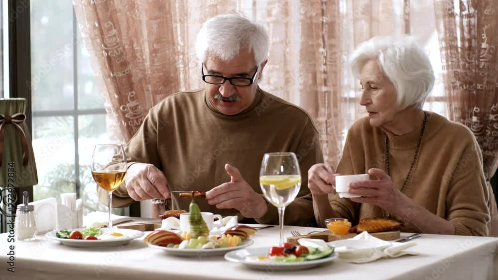 Waist-up shot of grumpy 60-something Caucasian man, sitting at ...