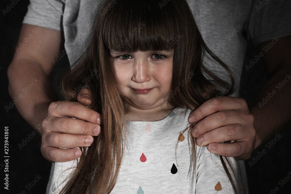 Crying little girl and adult man on dark background, closeup. Child in ...