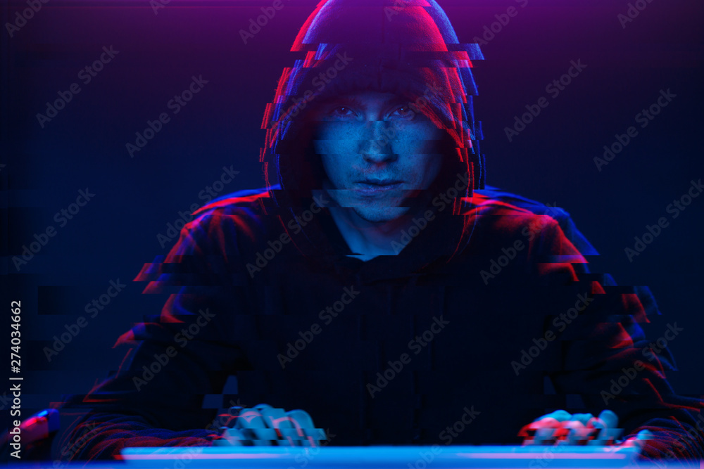 Hacker in the hood working with computer typing text in dark room ...
