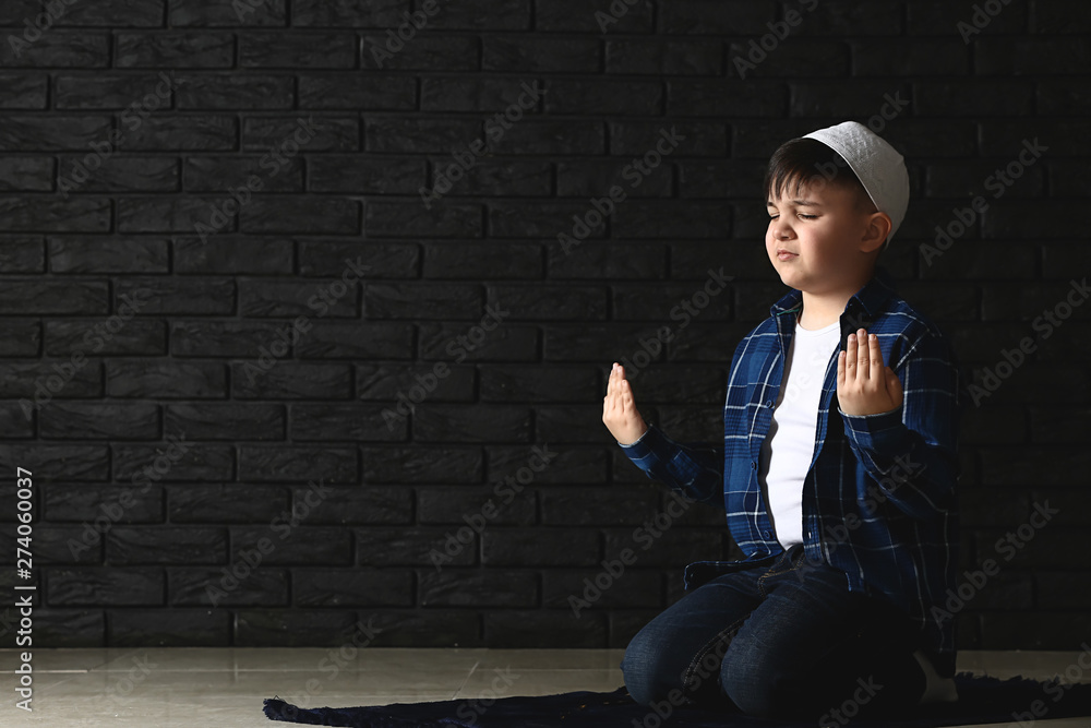 Little Muslim boy praying against dark wall Stock Photo | Adobe Stock