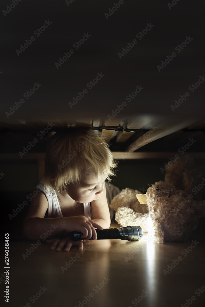 Foto de Little child, hiding under the bed, hugging teddy bear and ...