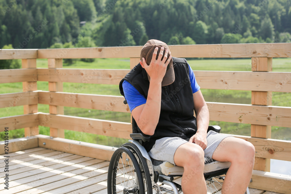 Disabled young man on a wheelchair in nature feeling depressed, lonely ...