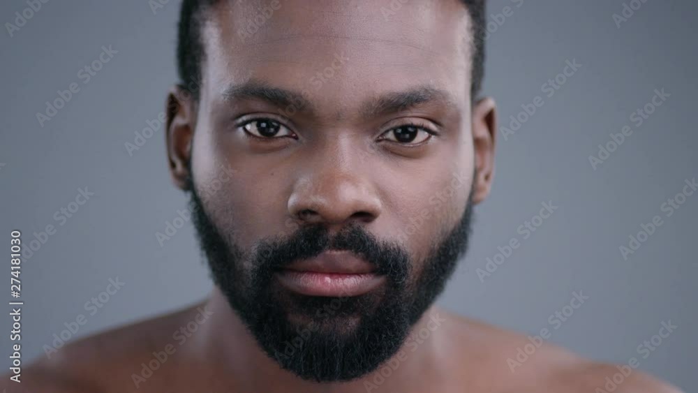 Close-up of beautiful african man face looking at camera on grey ...